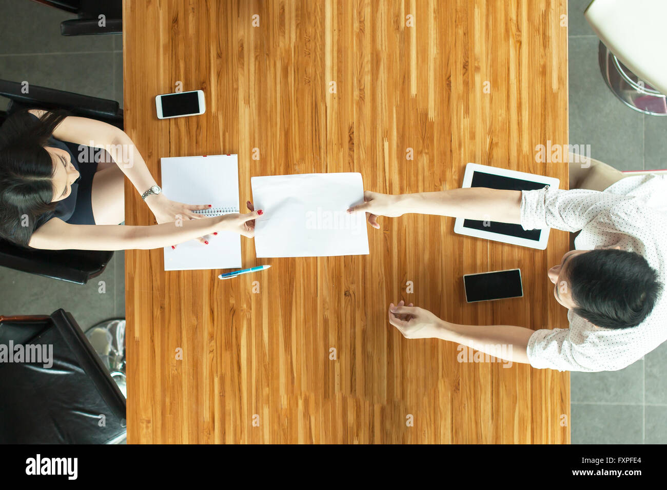 Top View of Business People sitting behind meeting desk, handing out ...