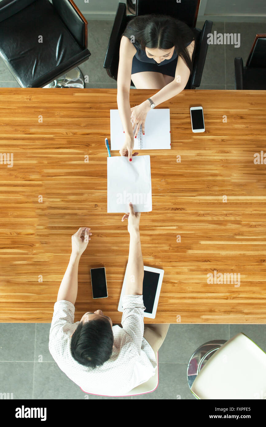 Top View of Business People sitting behind meeting desk, handing out ...
