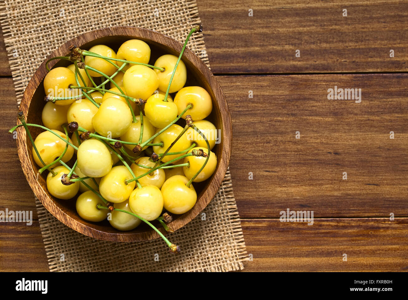 Ripe yellow or Rainier cherry in wooden bowl, photographed overhead on ...