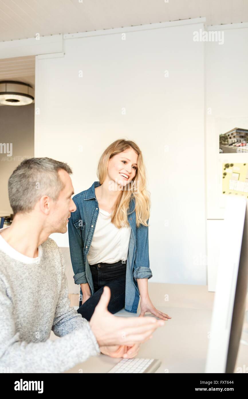 Colleagues using computer chatting and smiling Stock Photo - Alamy