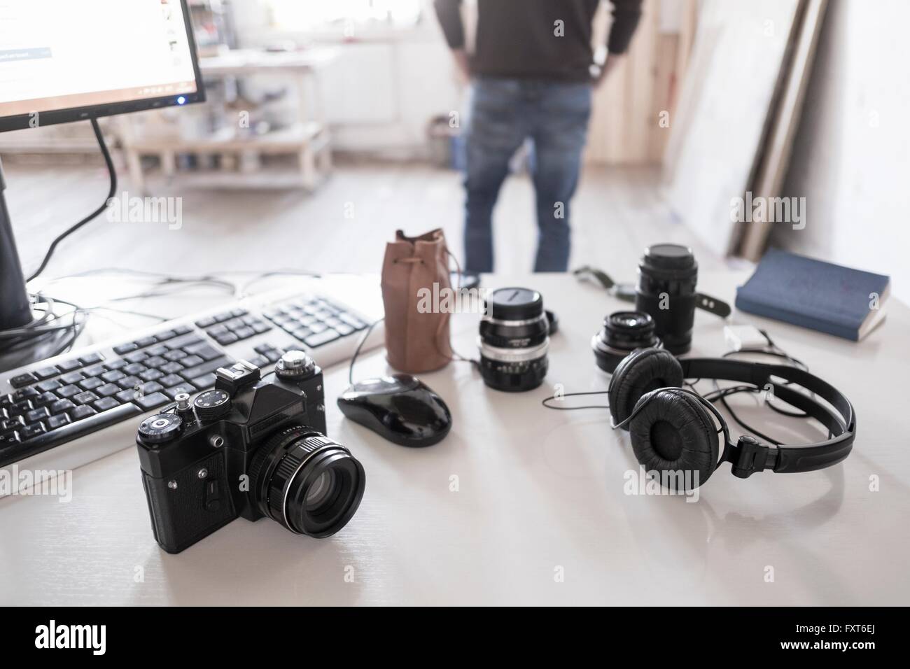 Camera, accessories and computer on desk, photographer in background ...