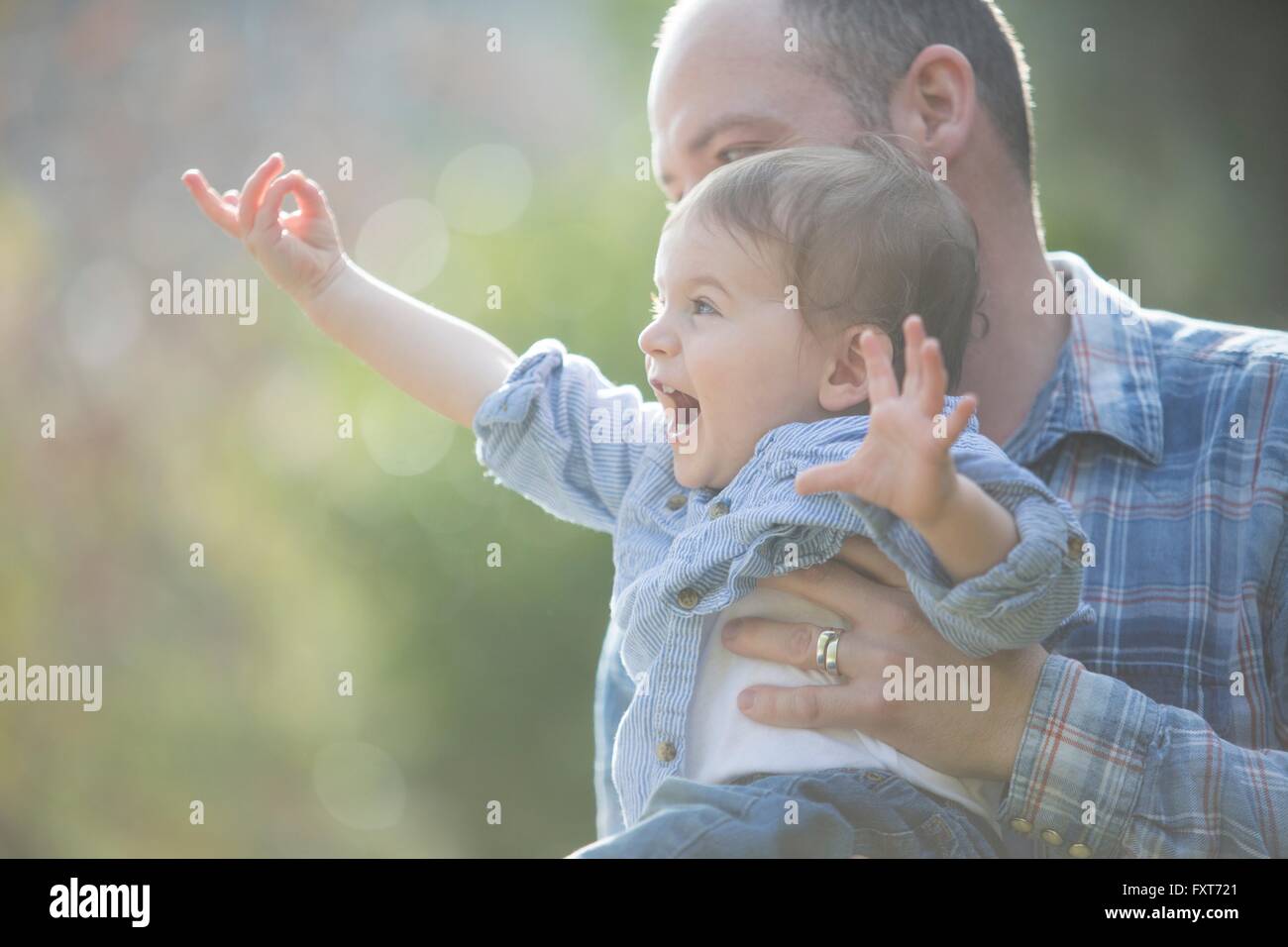 Side view of baby boy being held by father, pointing excitedly Stock ...