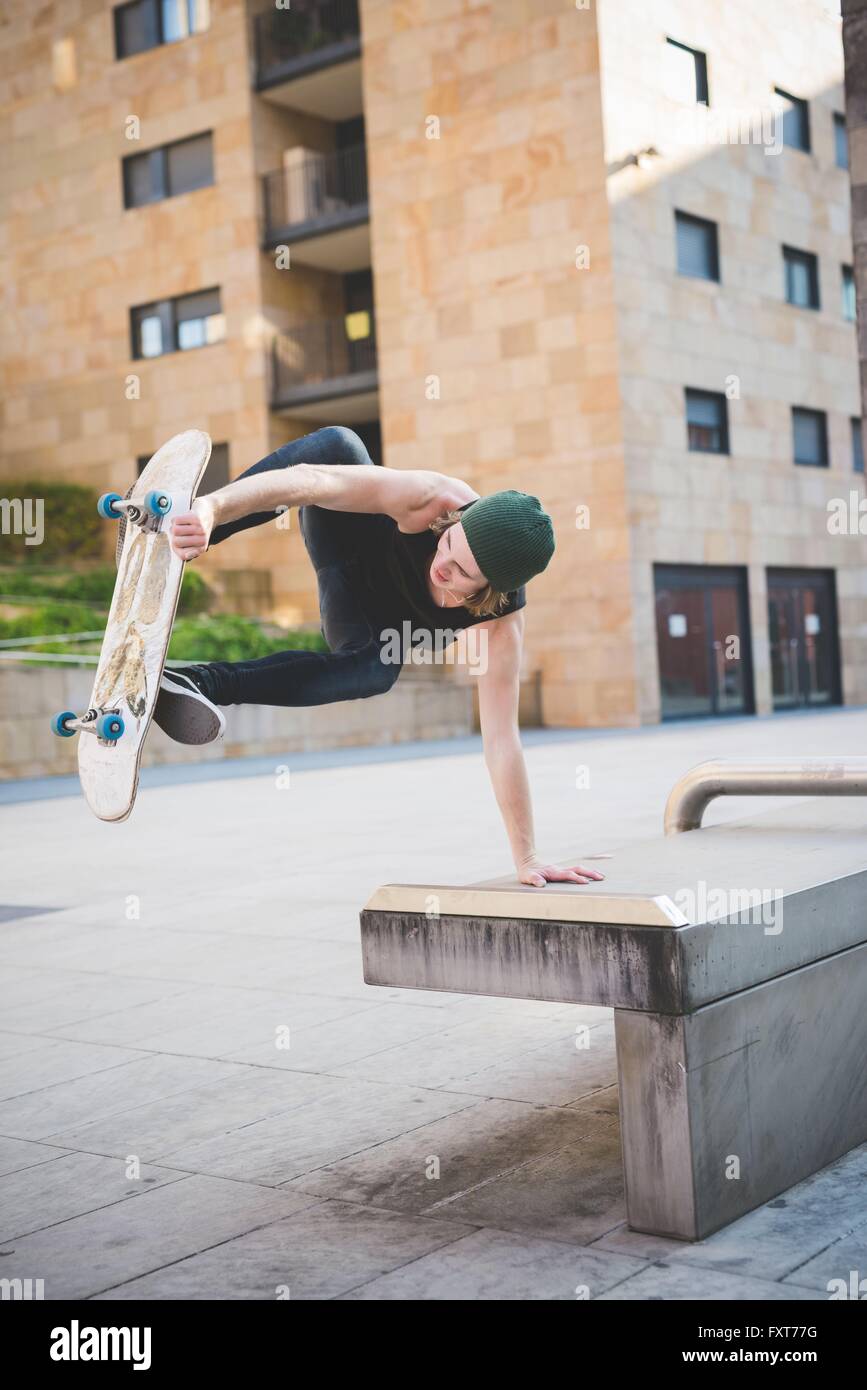 Young male skateboarder doing balance skateboard trick on urban ...