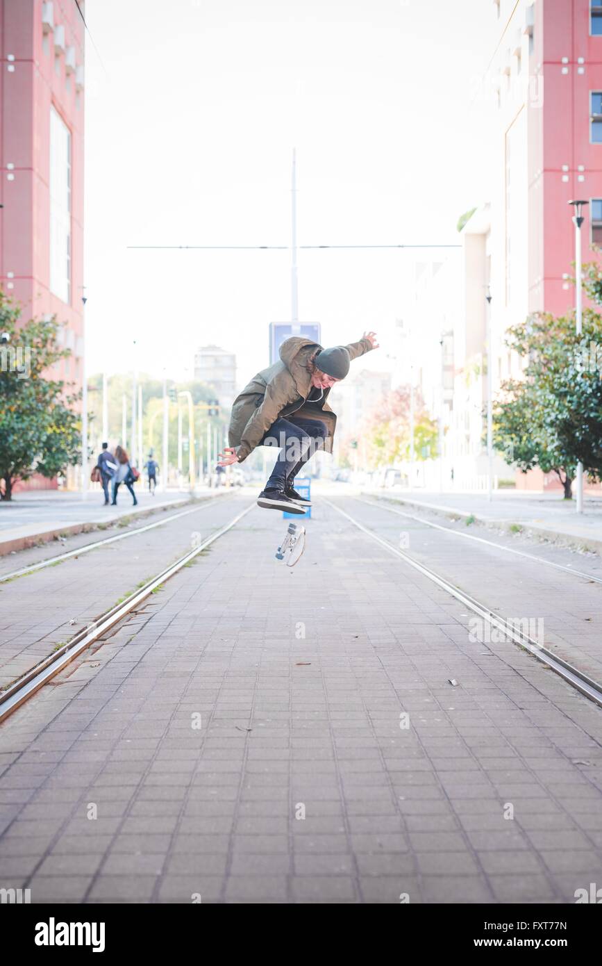 Young male skateboarder doing skateboarding jump on tramway Stock Photo ...