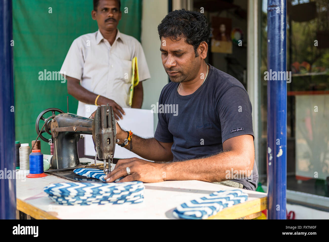Indian man making shoes in a makeshift workshop at the side of the road ...