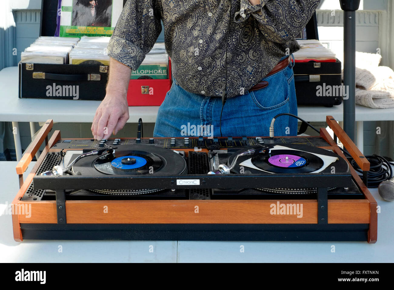 mature male dj playing traditional vinyl records at a street market ...