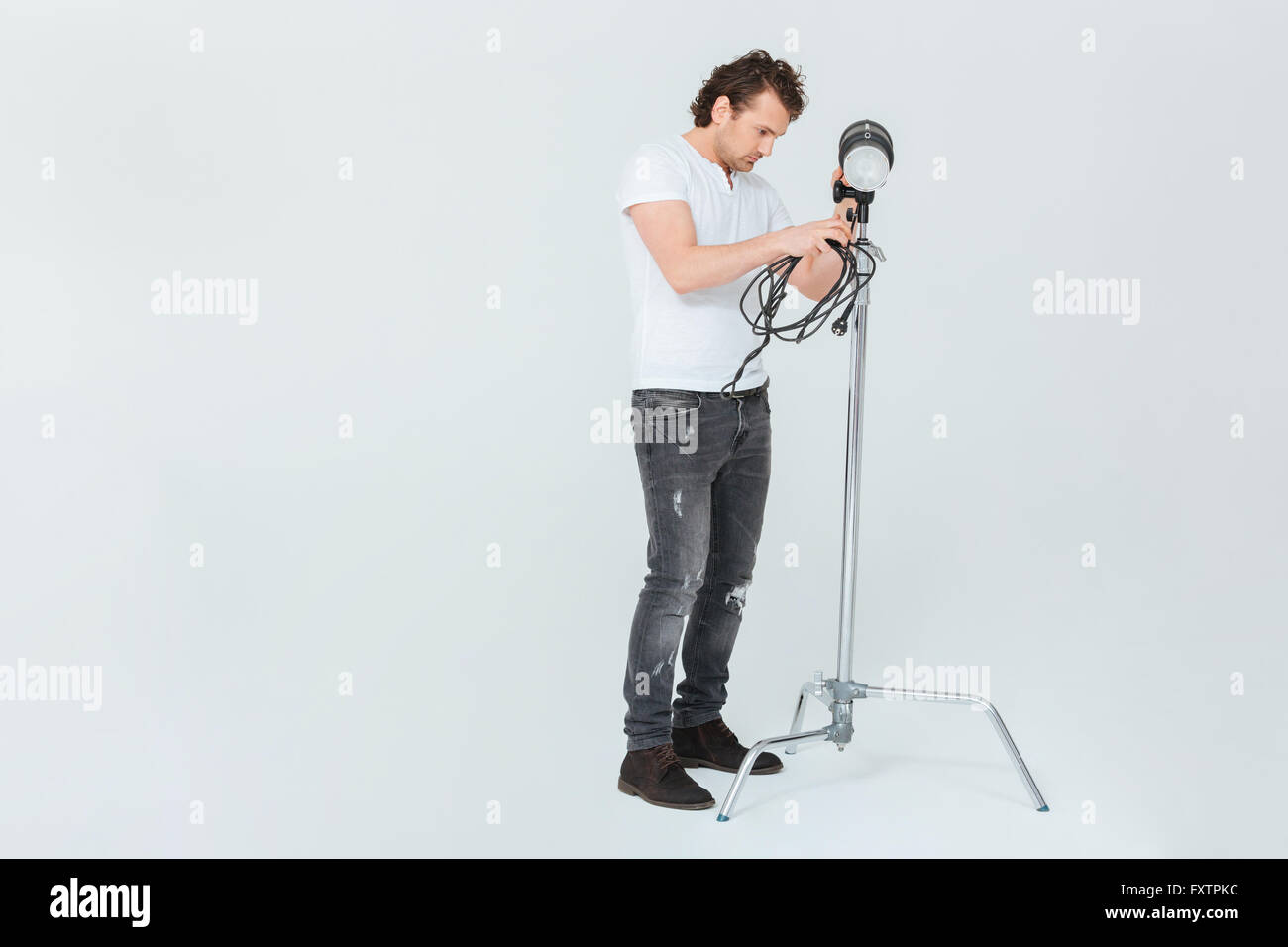 Male photographer preparing lighting equipment isolated on a white ...