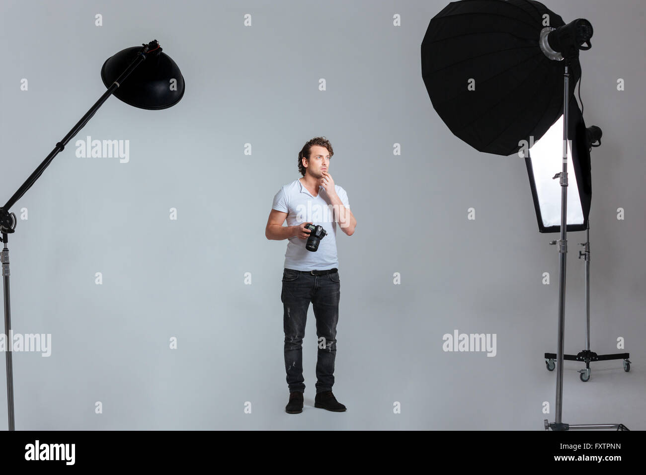 Pensive male photographer standing in professional studio with ...