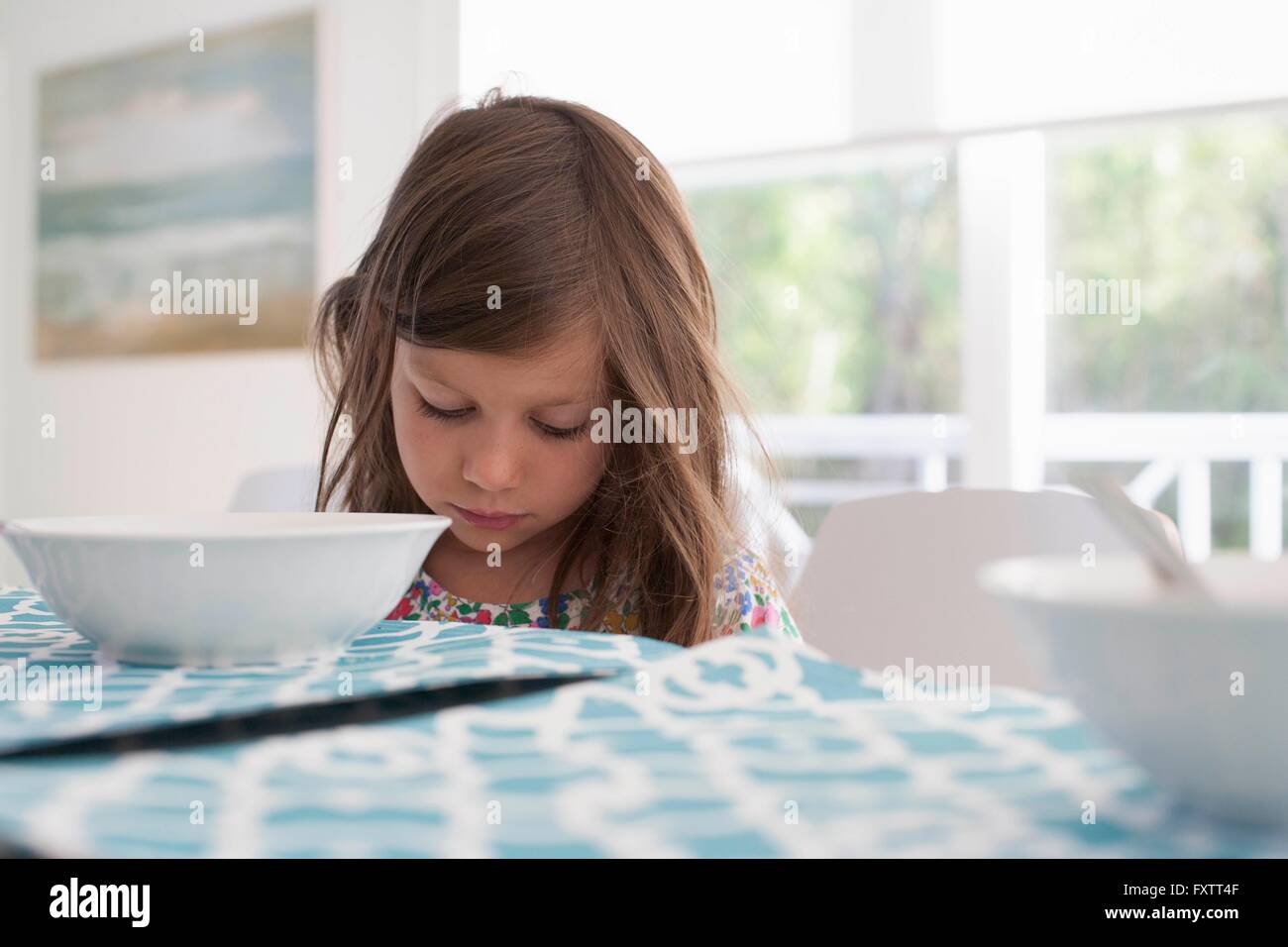 Girl at dining table looking down Stock Photo - Alamy
