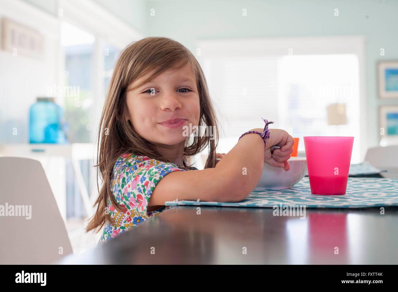 Girl at dining table eating breakfast looking at camera smiling Stock ...