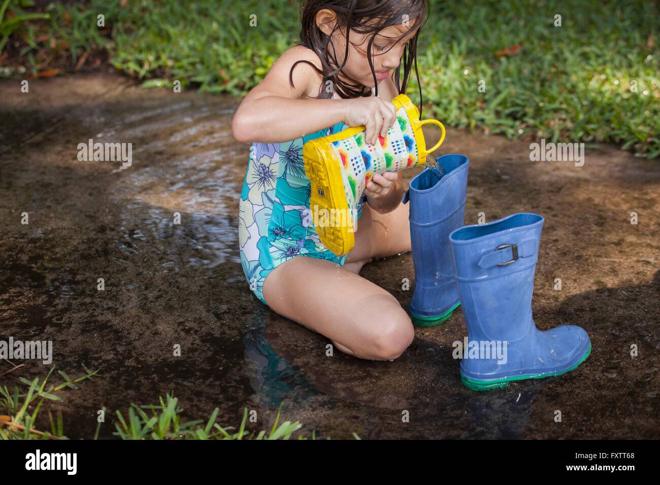 Girl filling wellies with water Stock Photo - Alamy