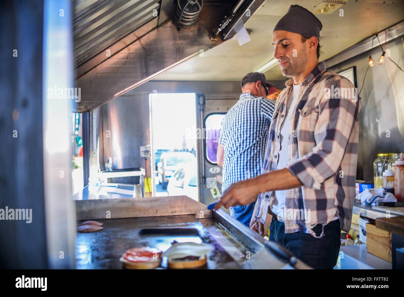 Young man in catering van cooking food on griddle Stock Photo - Alamy