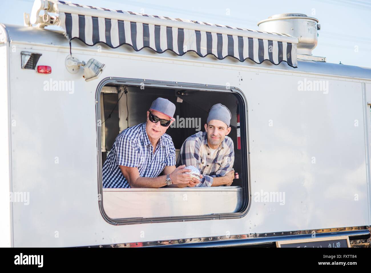 Men wearing chefs hats looking out of catering van hatch Stock Photo ...