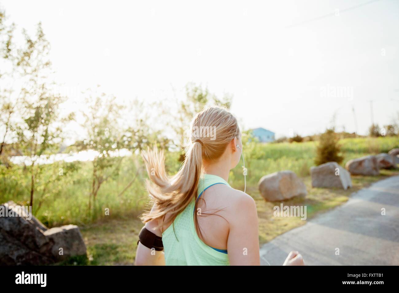 Head and shoulders of woman wearing activity tracker jogging on path ...