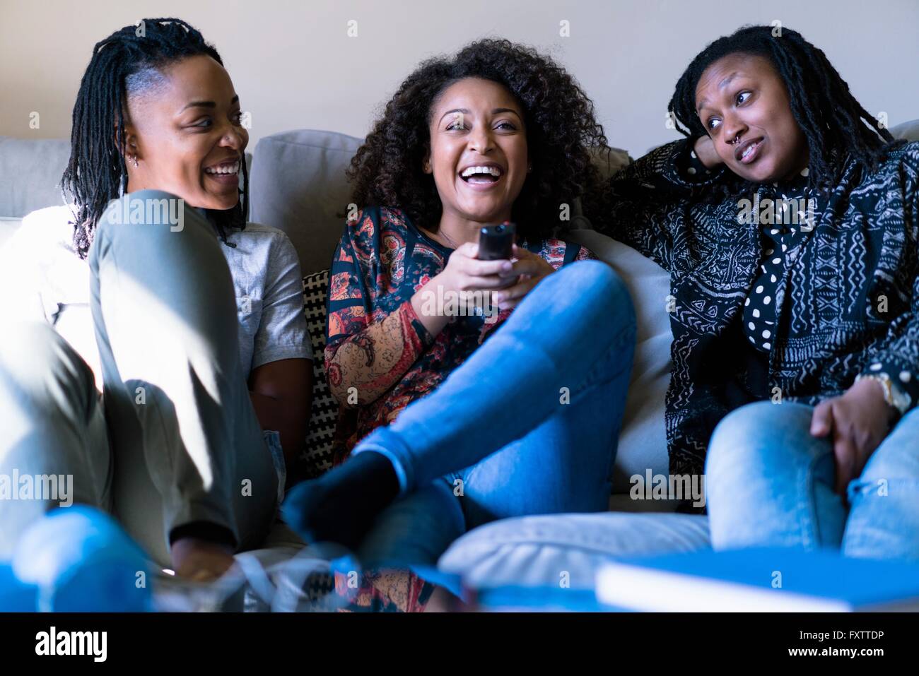 Three female friends, sitting on sofa, relaxing Stock Photo - Alamy