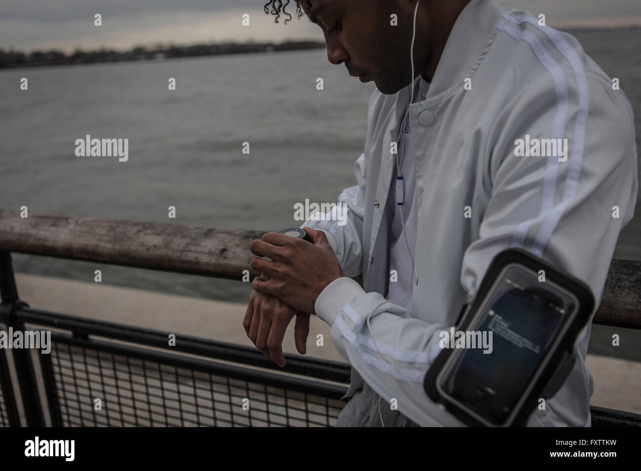 Young man training on riverside at dawn timing on smartwatch Stock ...
