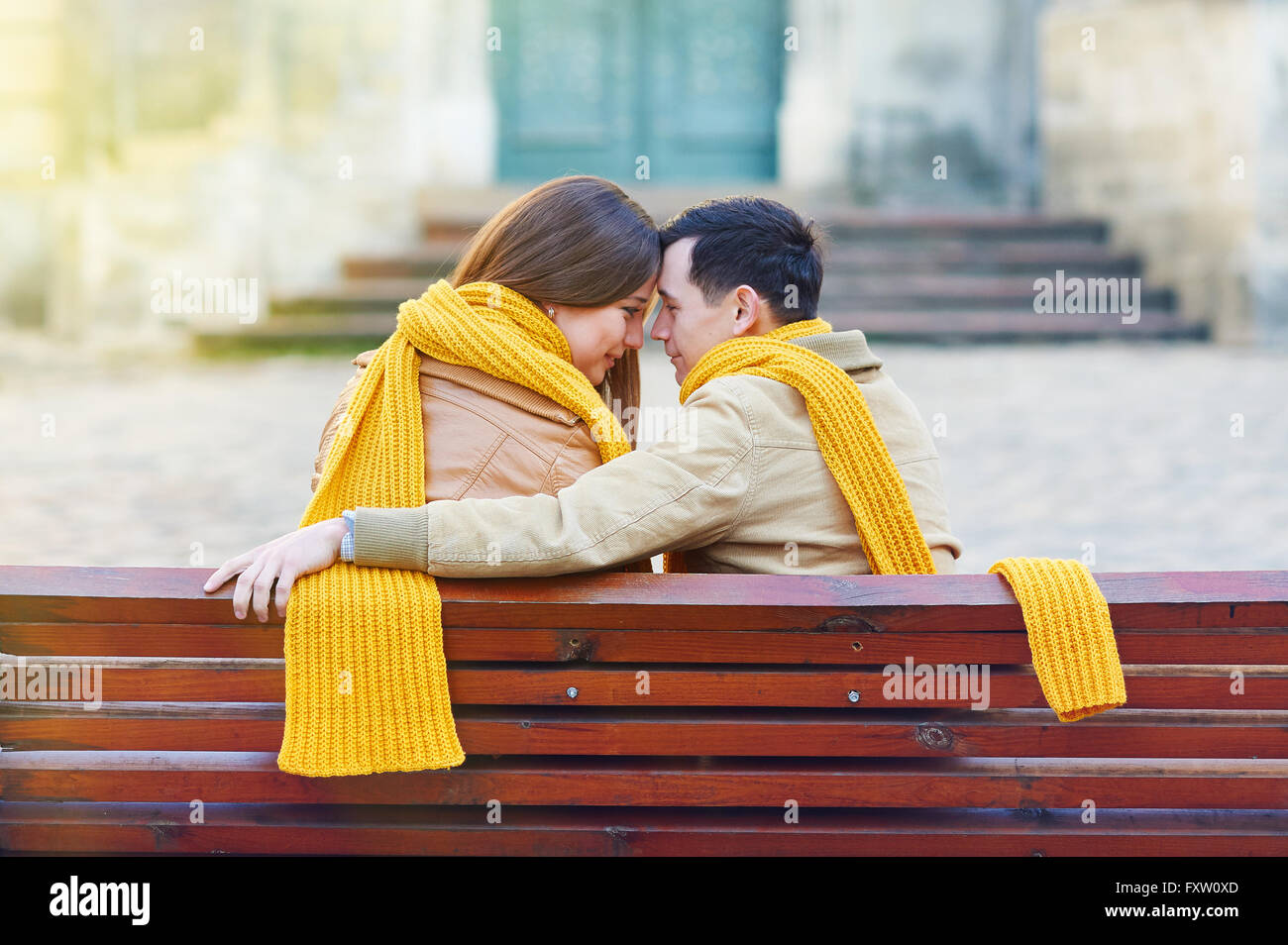 Two lovers sitting on bench in park and holding themselves by hands ...