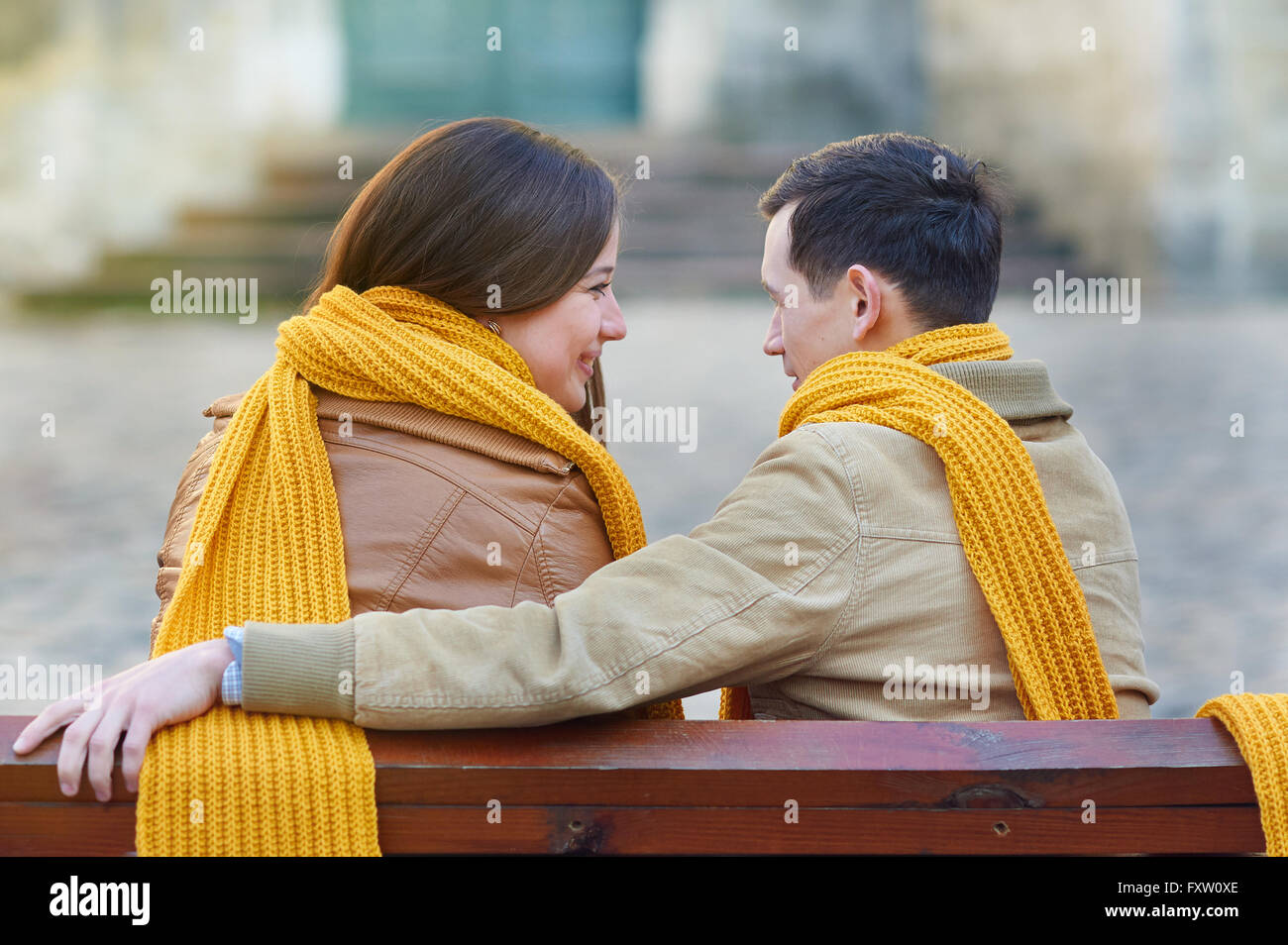 Two lovers sitting on bench in park and holding themselves by hands ...