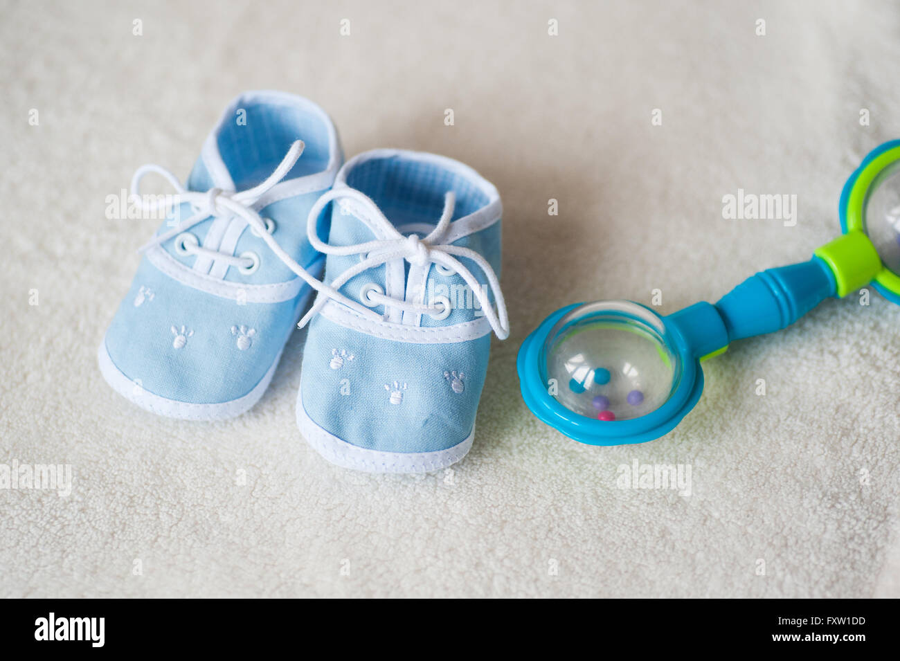 baby shoes and rattle on light background Stock Photo - Alamy