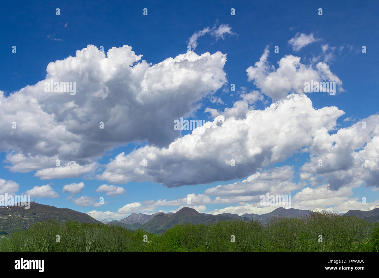 Mountain landscape in spring day, blue sky and big clouds above green ...