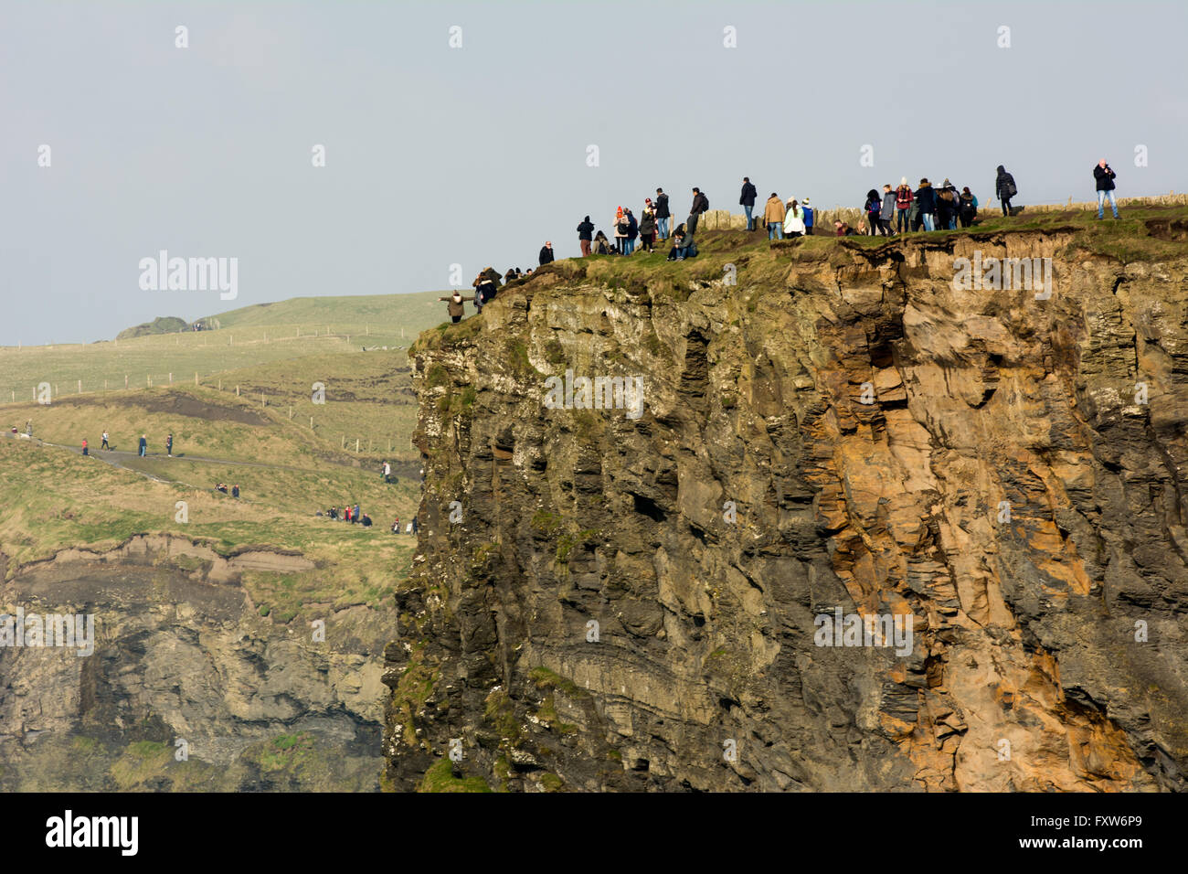 People standing on the edge of the Cliffs of Moher on west coast of ...