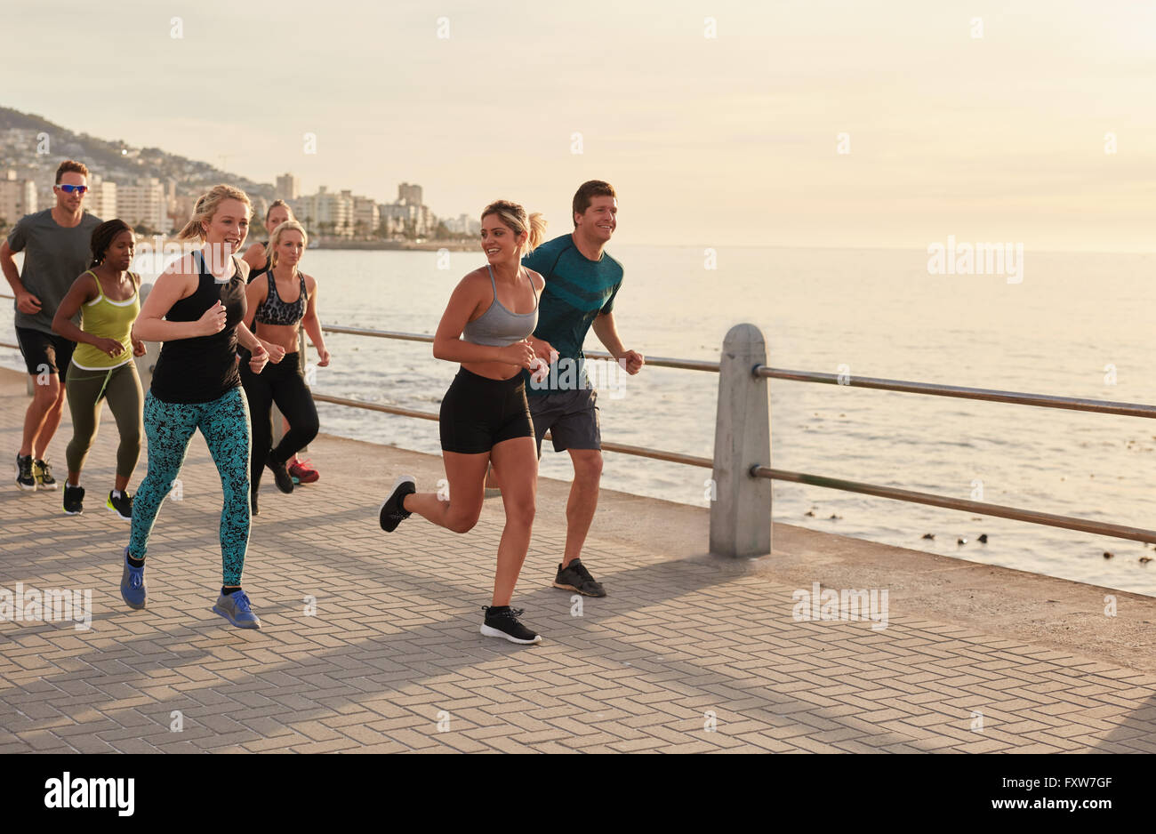 Young runners workout along a seaside promenade. Running club group ...