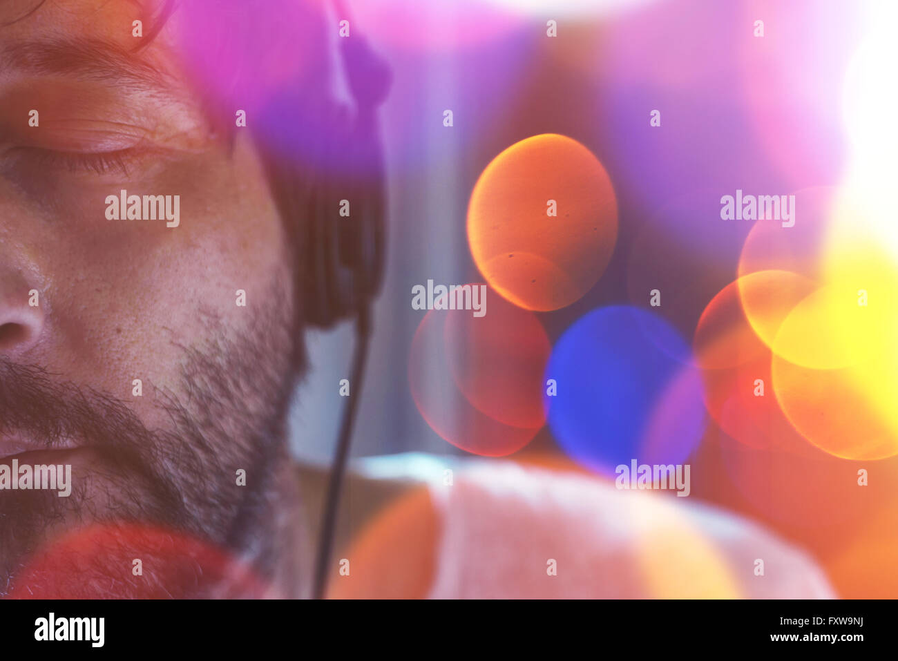 Half face low key portrait of adult unshaven man listening to music on ...
