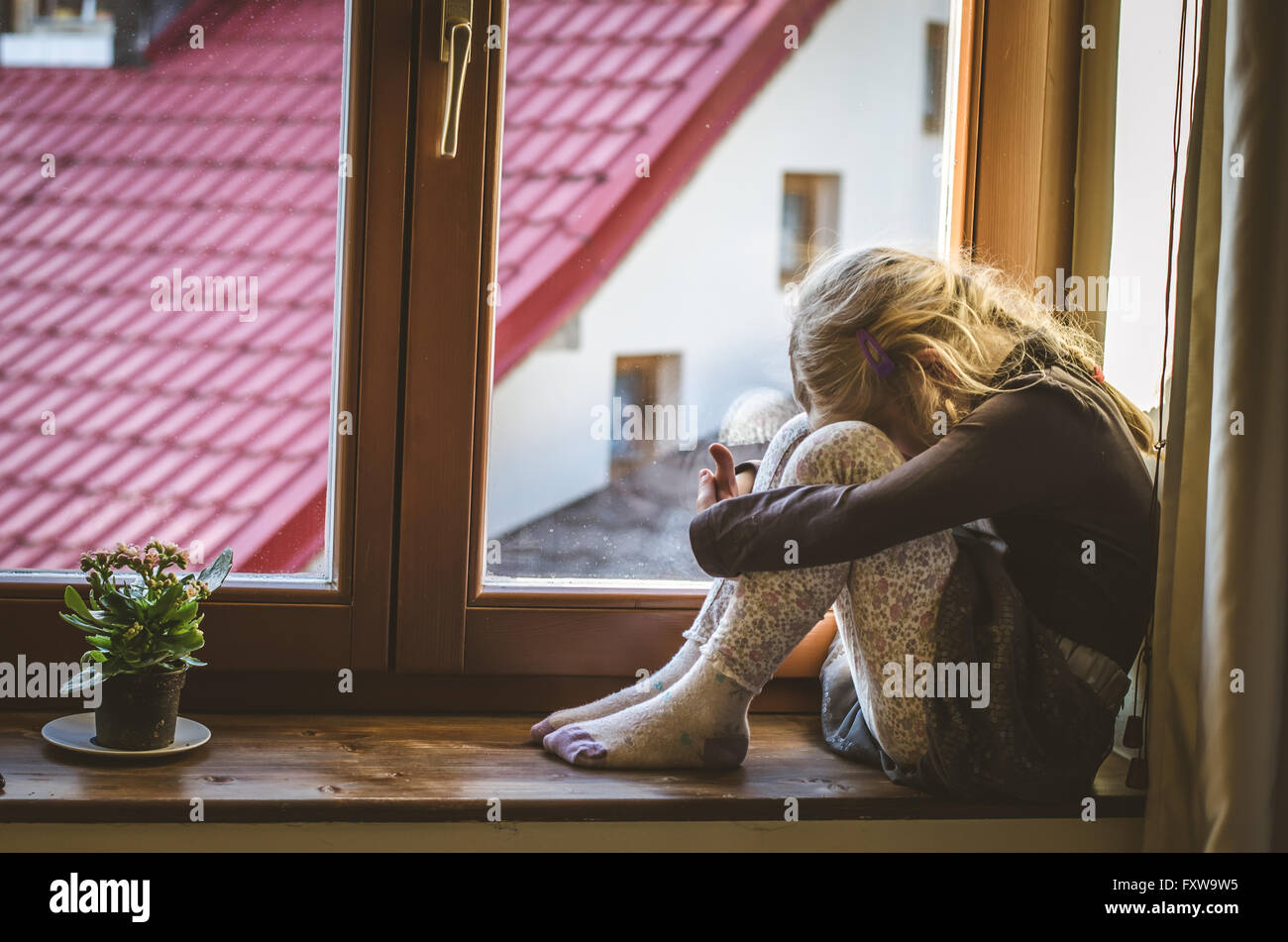 lonely girl sitting by the window Stock Photo - Alamy