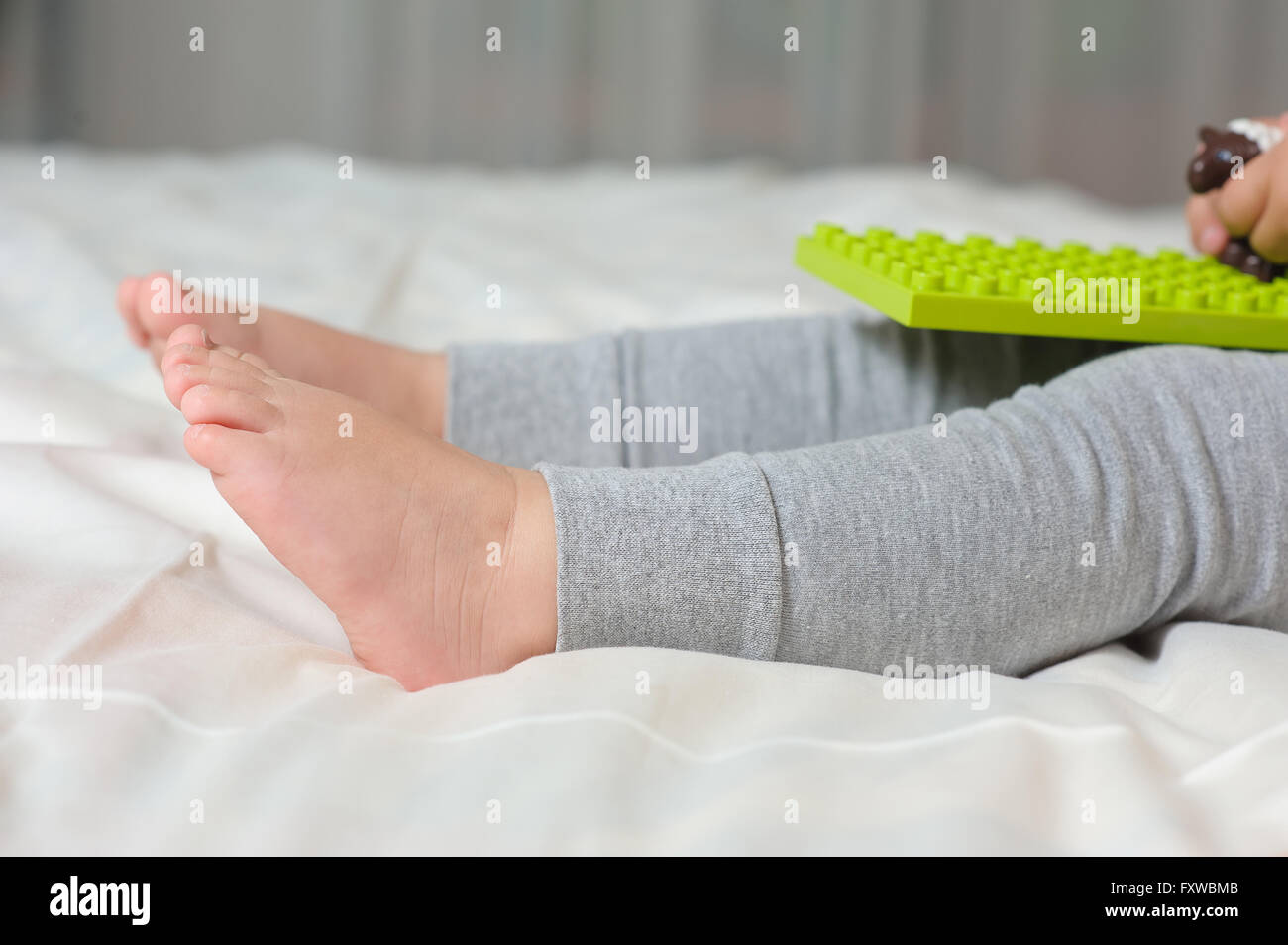 Legs of child sitting on the bed Stock Photo - Alamy