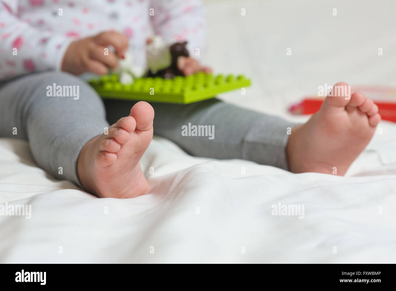 Legs of child sitting on the bed Stock Photo - Alamy
