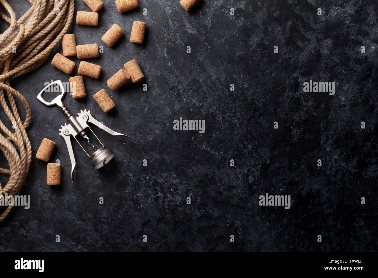 Wine corks and corkscrew over dark stone background. Top view with copy ...