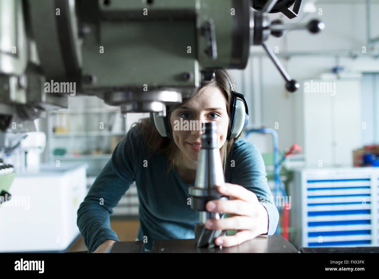 Woman in workshop wearing ear defenders operating machine smiling Stock ...