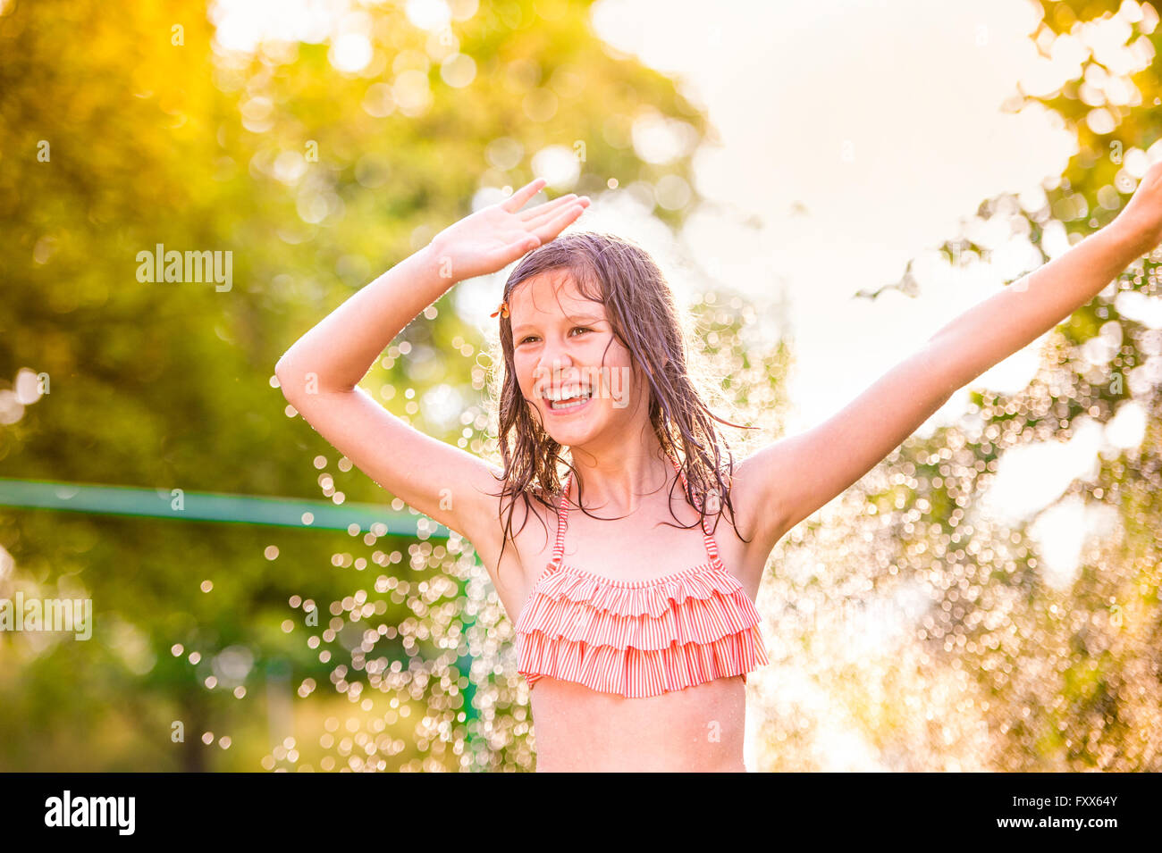 Girl in bikini dancing at the sprinkler, summer garden Stock Photo - Alamy