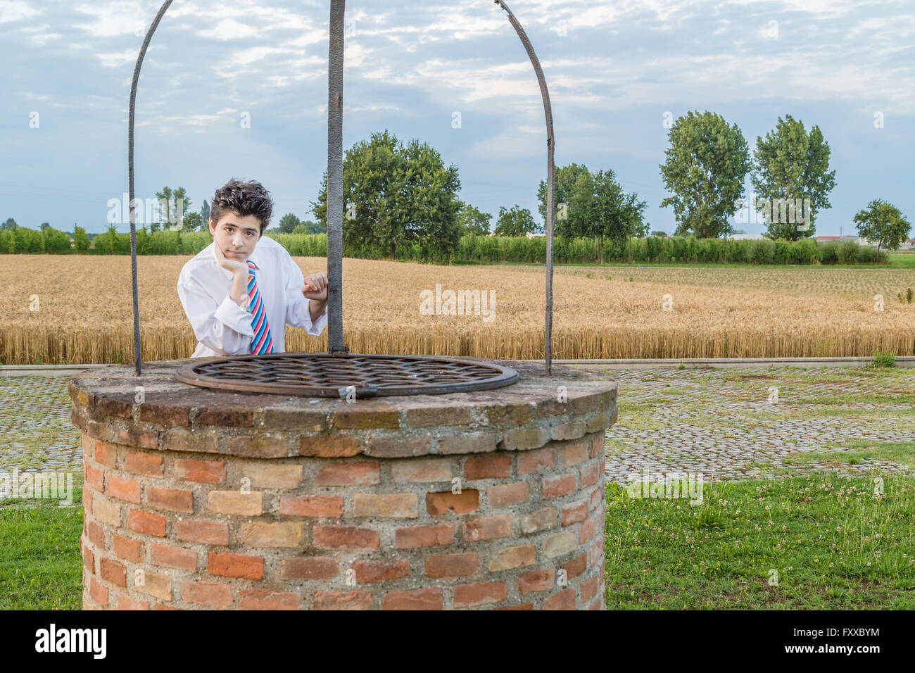 Teenage Boy looks out over an old well in the countryside of Emilia ...