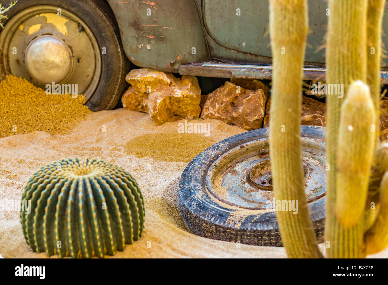 carcass of an old rusty car in the desert sand surrounded by rocks and ...
