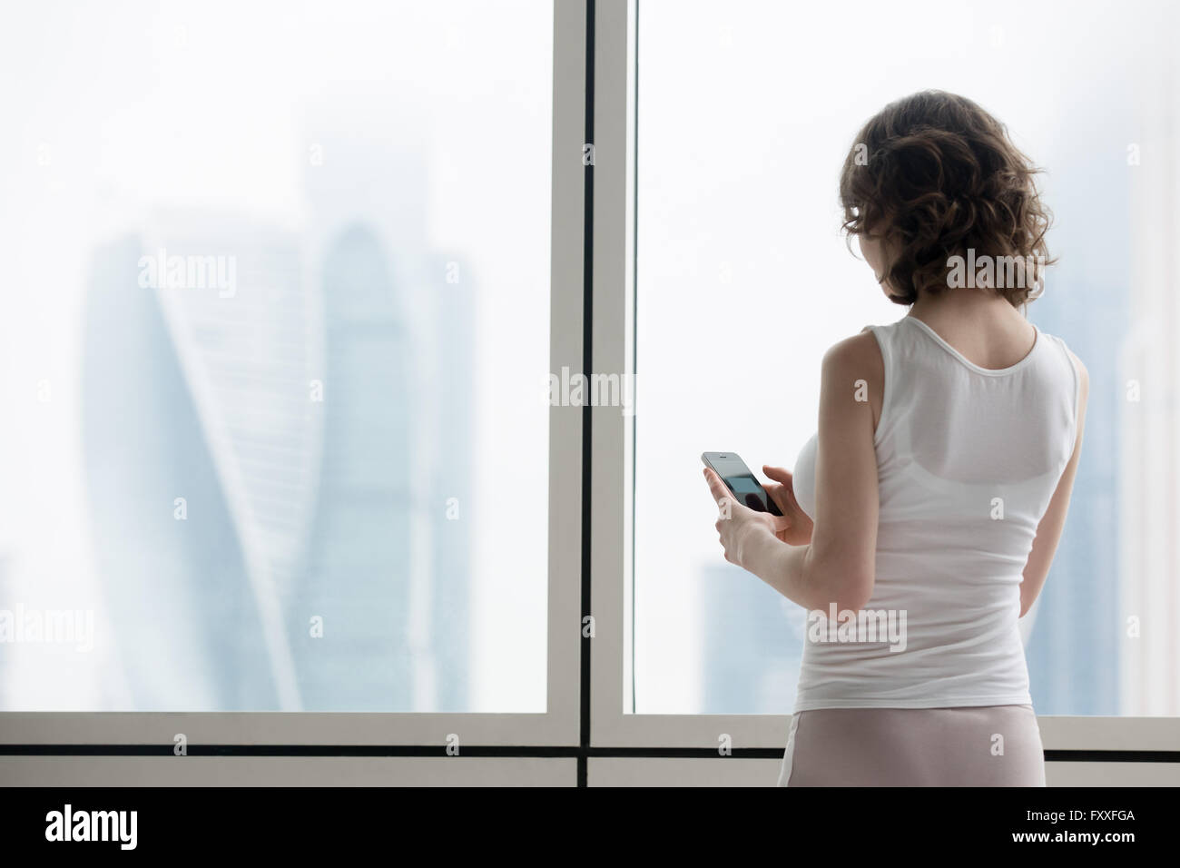 Back view of young woman making call using smartphone. Caucasian model ...