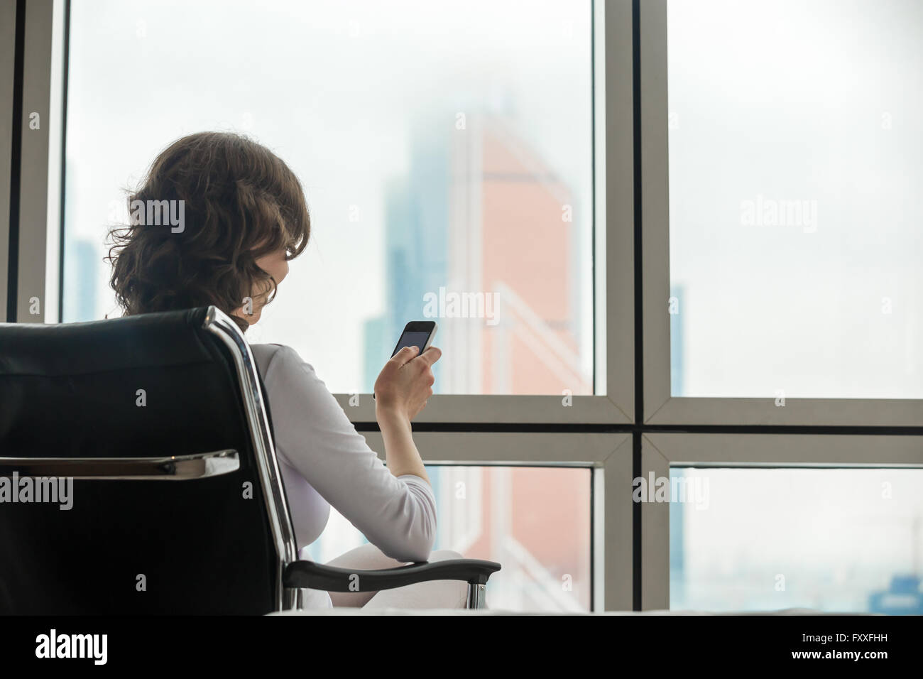 Back view of young successful business lady making call using smart ...