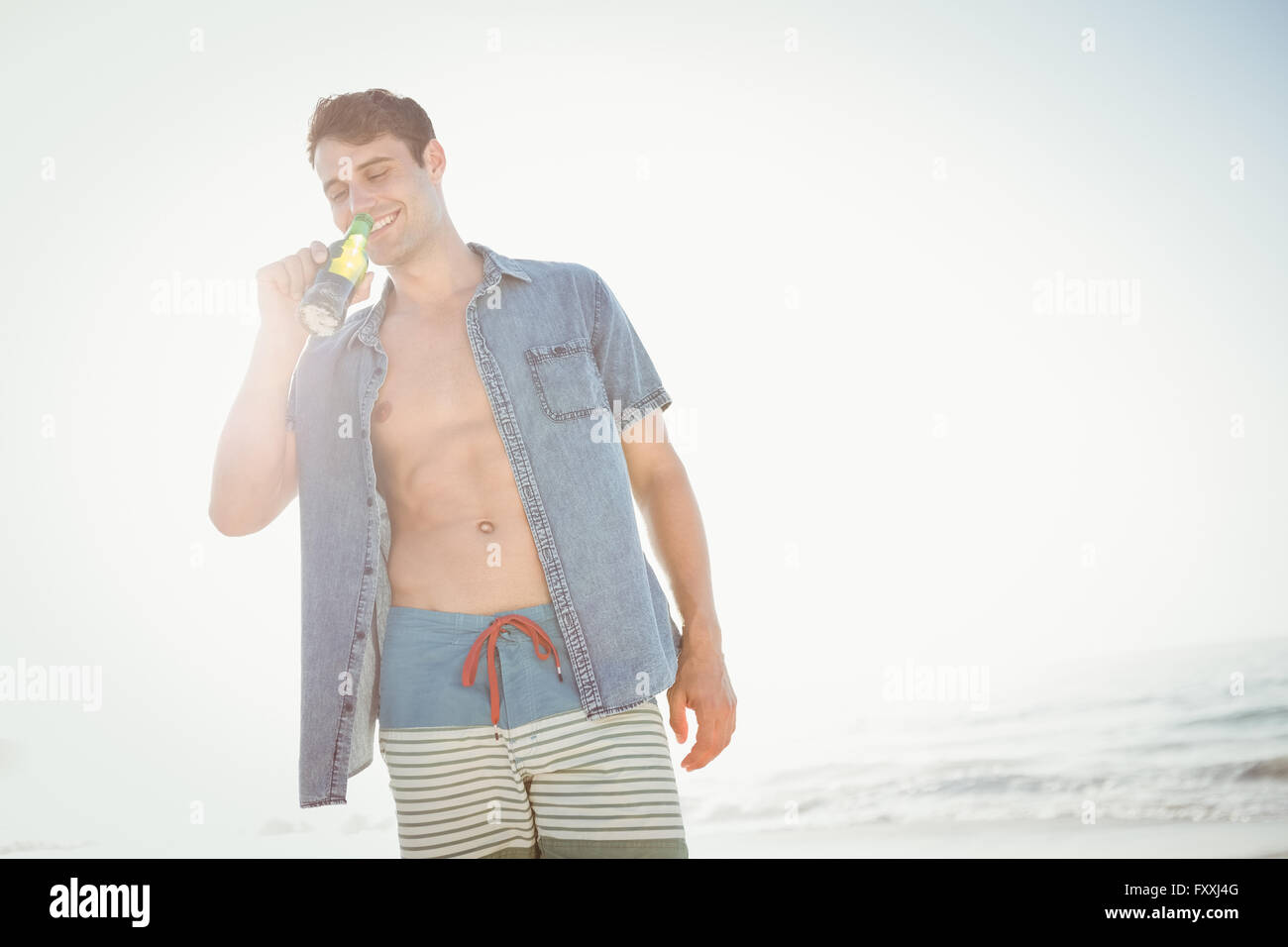 Smiling man drinking beer on the beach Stock Photo - Alamy