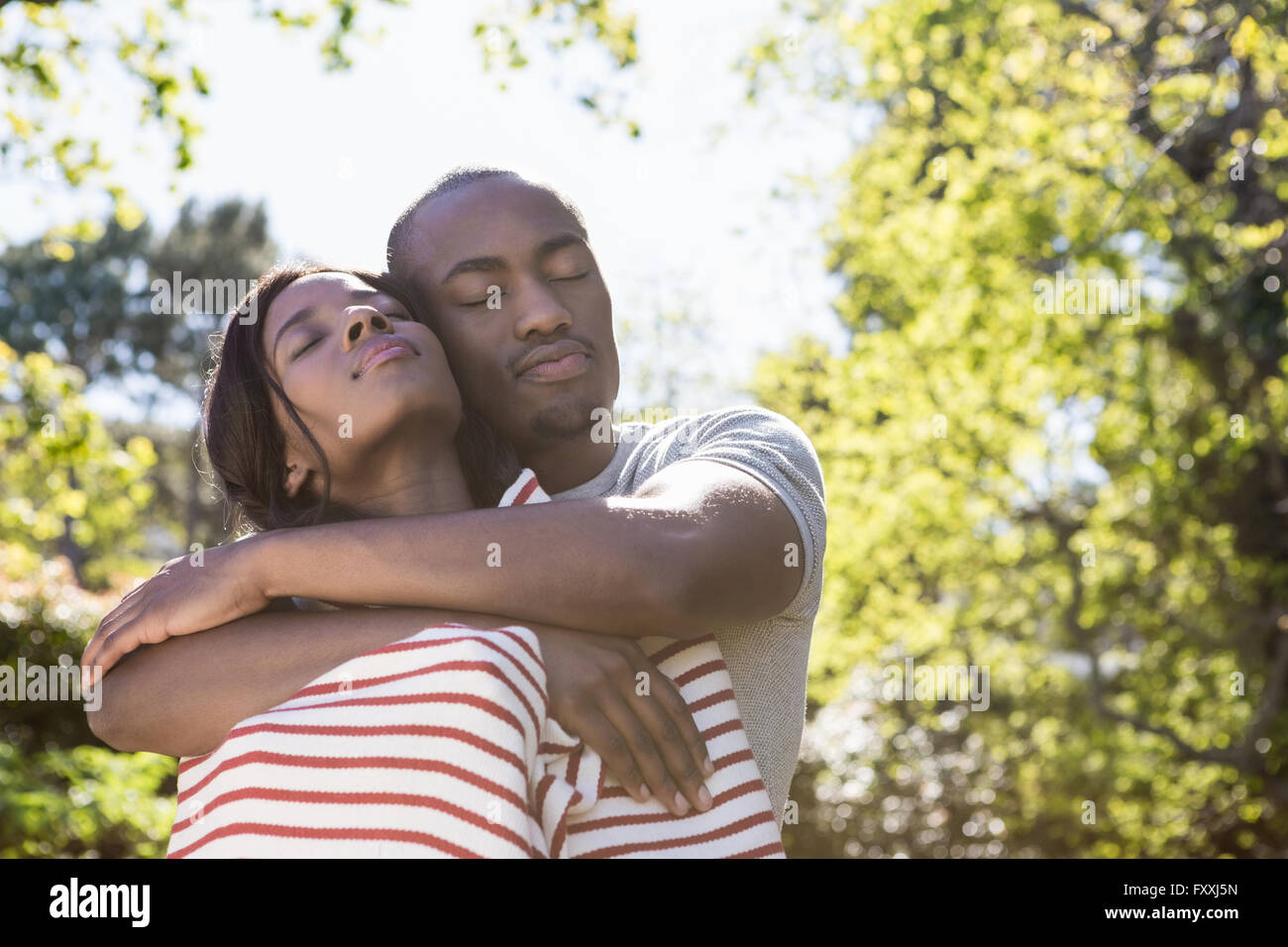 Young couple cuddling in the park Stock Photo - Alamy