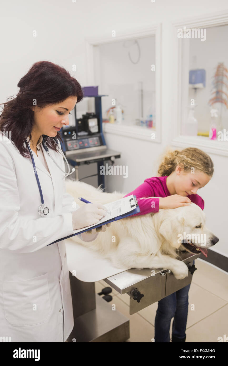 Girl holding her pet dog while vet examining Stock Photo - Alamy