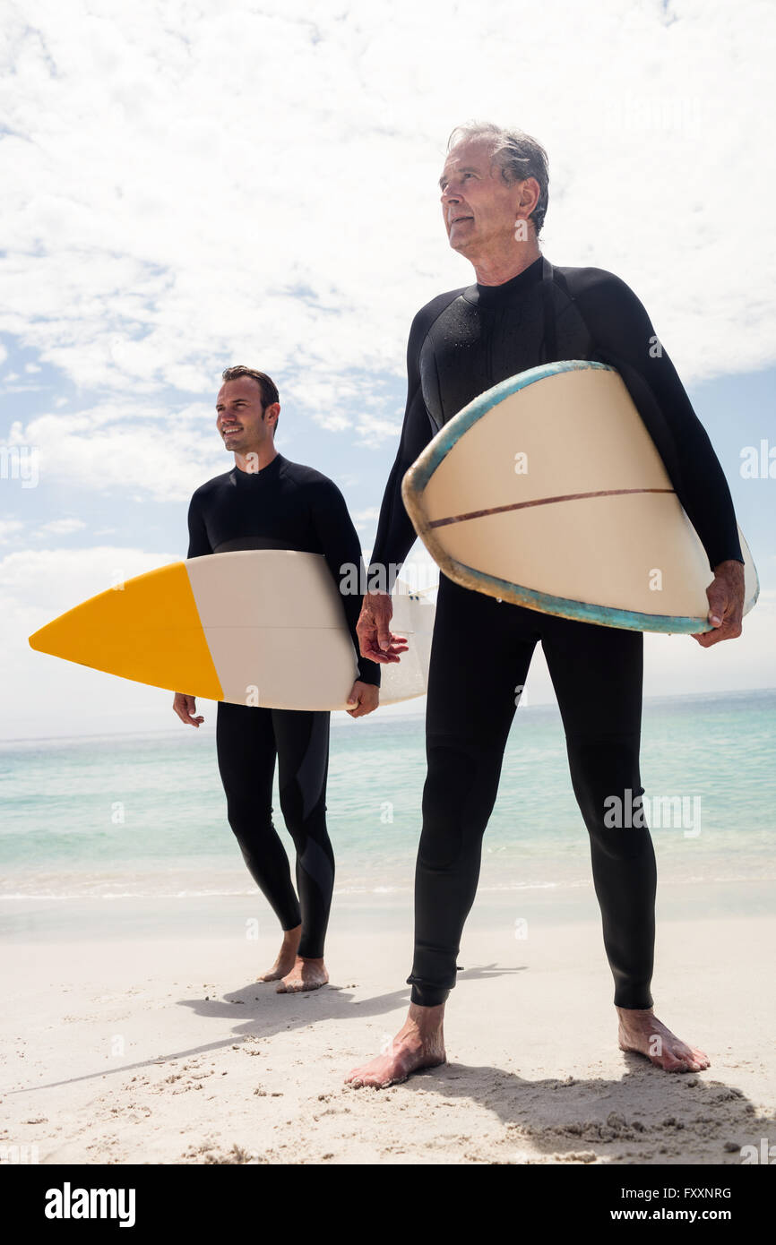Father and son standing with surfboard and looking at a distance Stock ...