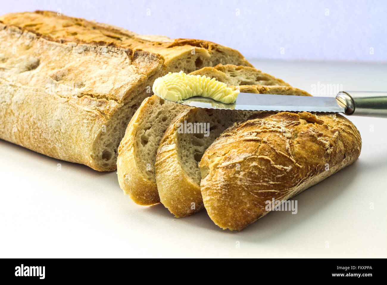 Big bread cut in slices with a knife full of butter Stock Photo - Alamy