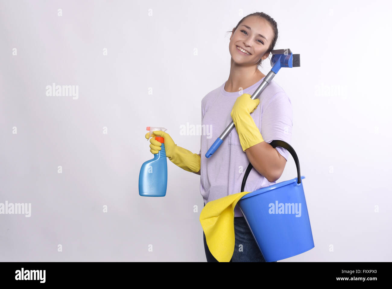 Portrait of young woman holding cleaning products. Isolated on white ...