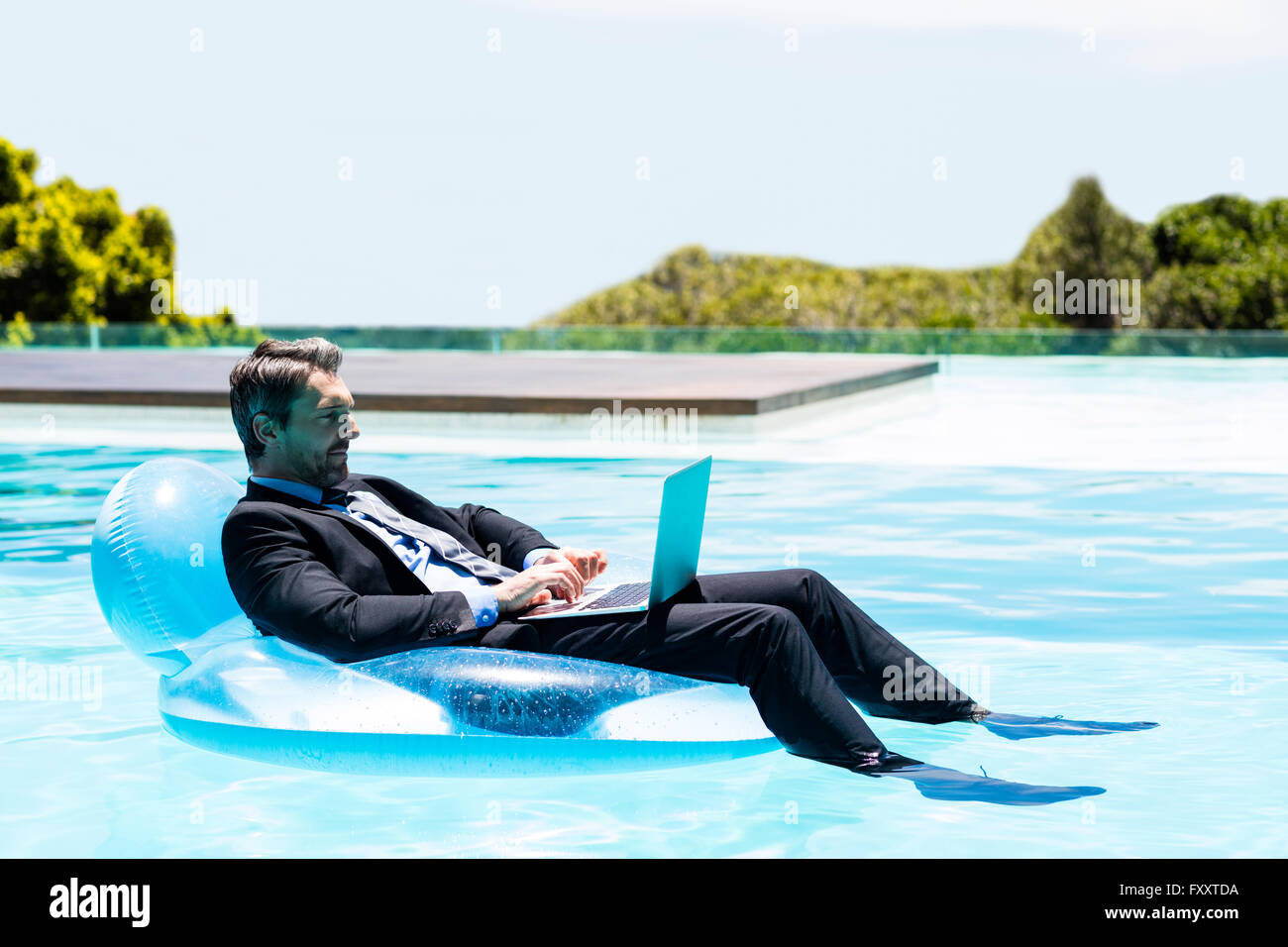 Businessman using laptop on inflatable Stock Photo - Alamy
