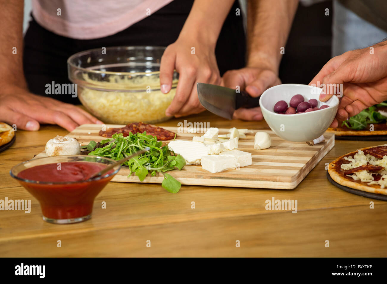 Mid section of friends preparing pizza Stock Photo - Alamy