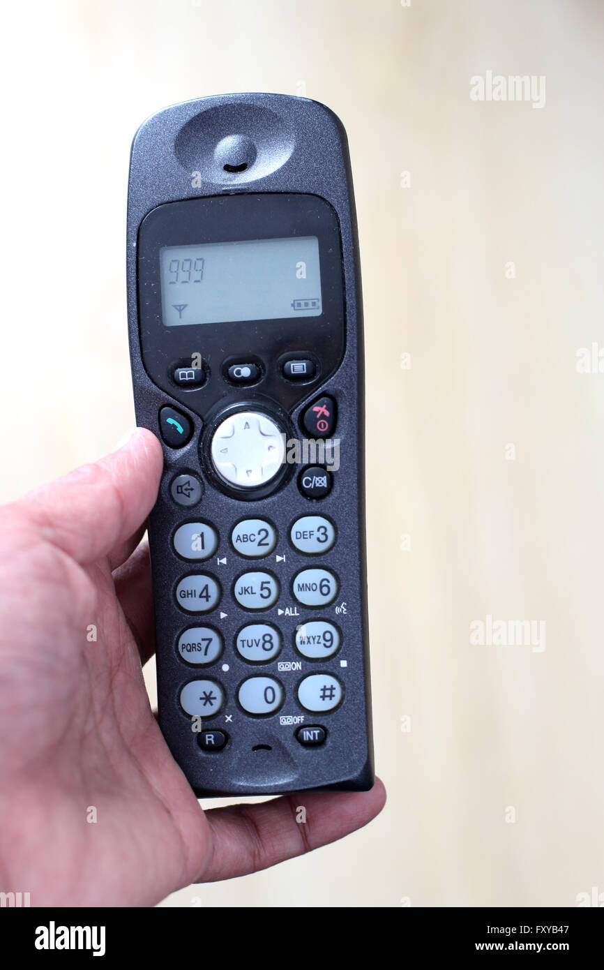 Close up image of hand holding home phone with 999 on the screen Stock ...