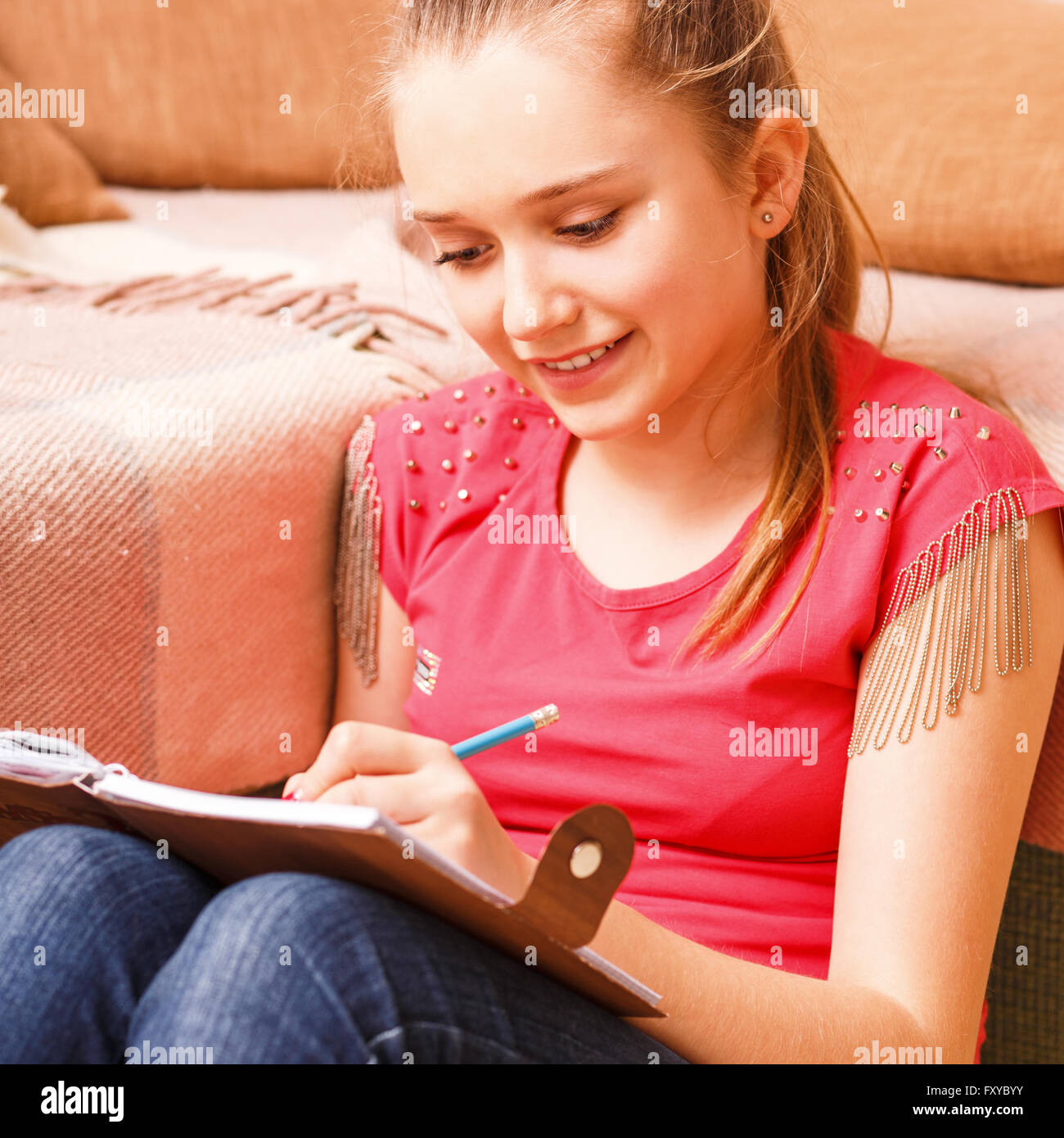 Young happy smiling teenager girl writing in diary notebook sitting on ...