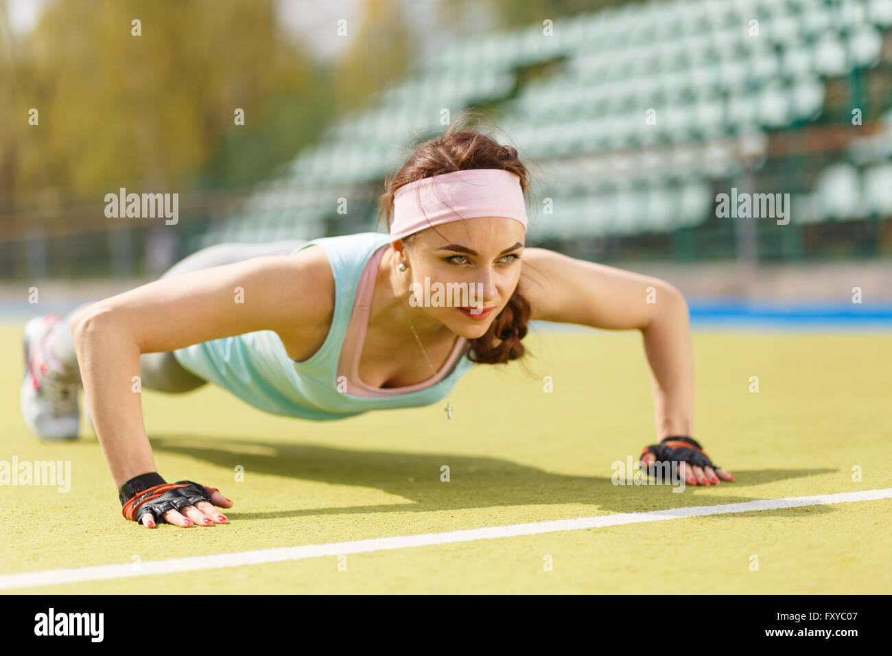 Young sporty woman doing push up exercise outdoors workout. Smiling ...