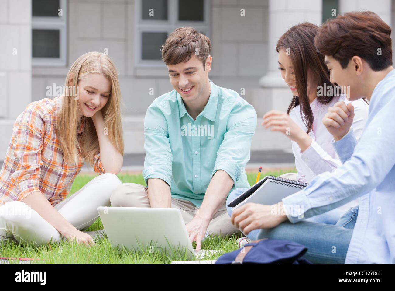 Domestic and international college students seated on a grass together ...