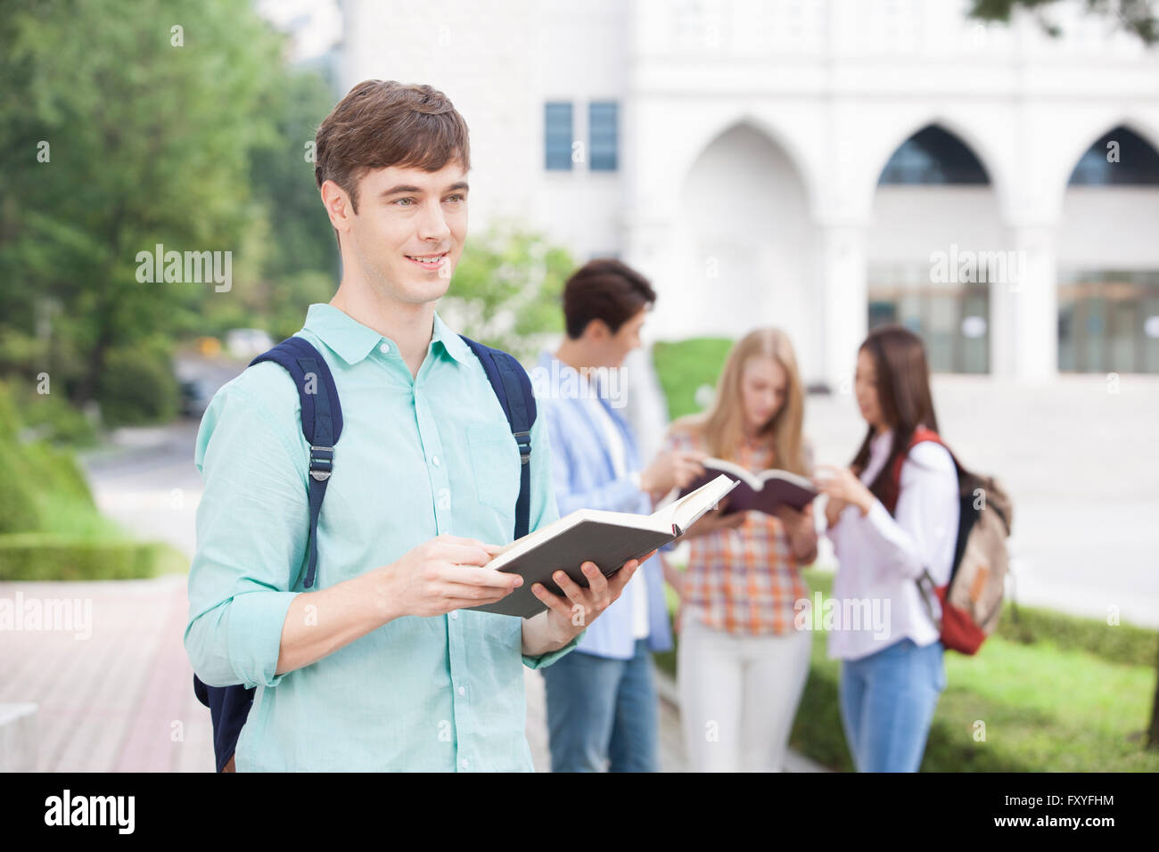 International student in college with backpack holding a book and ...